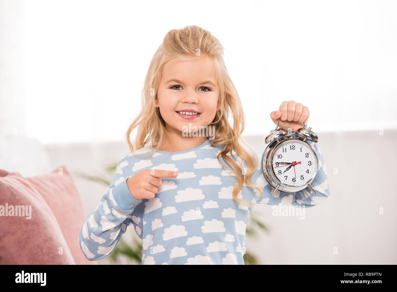 smiling cute child pointing with finger at clock Stock Photo - Alamy