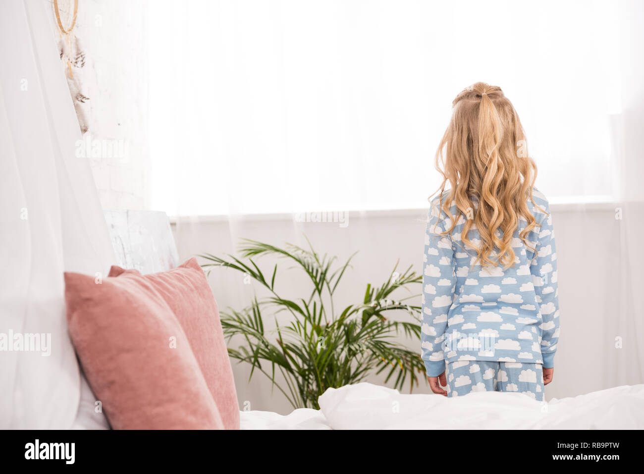 back view of child in pajamas standing near window in bedroom Stock ...