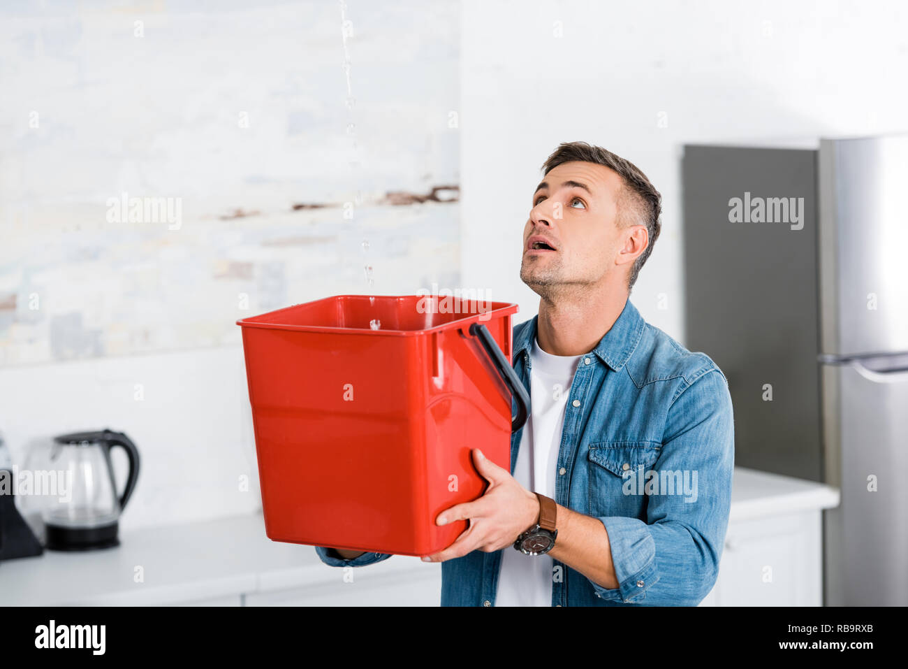 handsome man holding plastic bucket and looking at ceiling Stock Photo ...