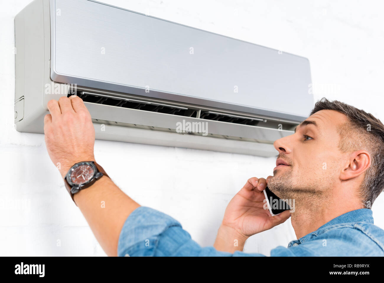 handsome man talking on smartphone while checking air conditioner Stock ...