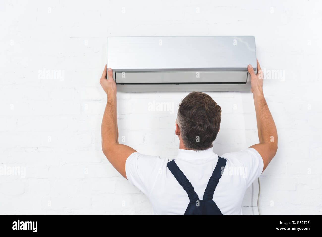 back view of repairman fixing air conditioner Stock Photo - Alamy