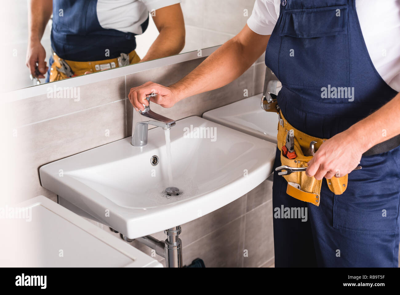 cropped view of repairman checking faucet after repairing and holding ...