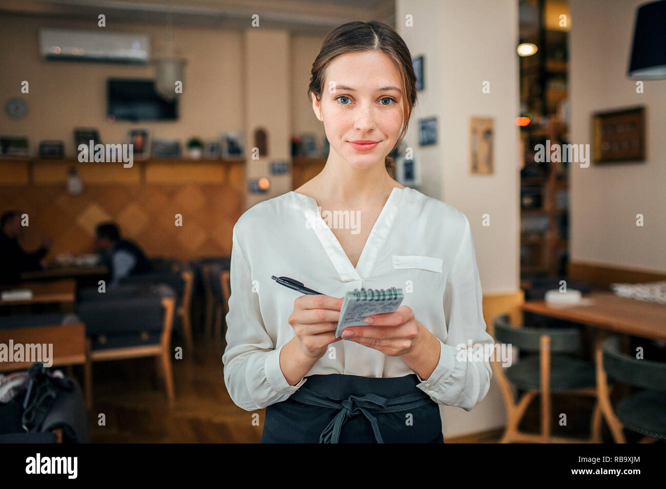 Confident young waitress stand in restaurant and look straight on ...