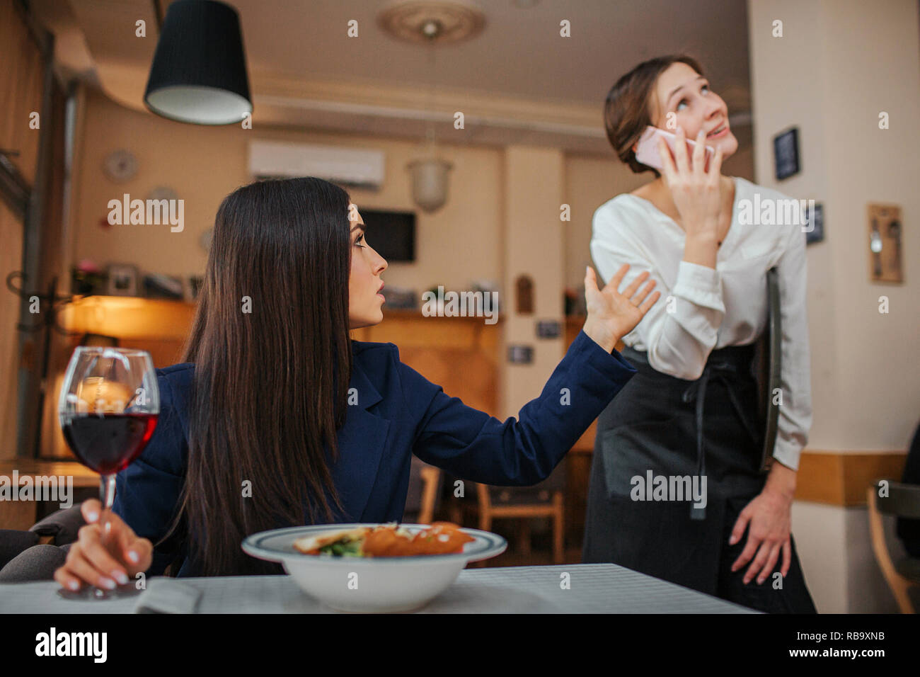 Young businesswoman sit at table and call waitress. Woman in white ...