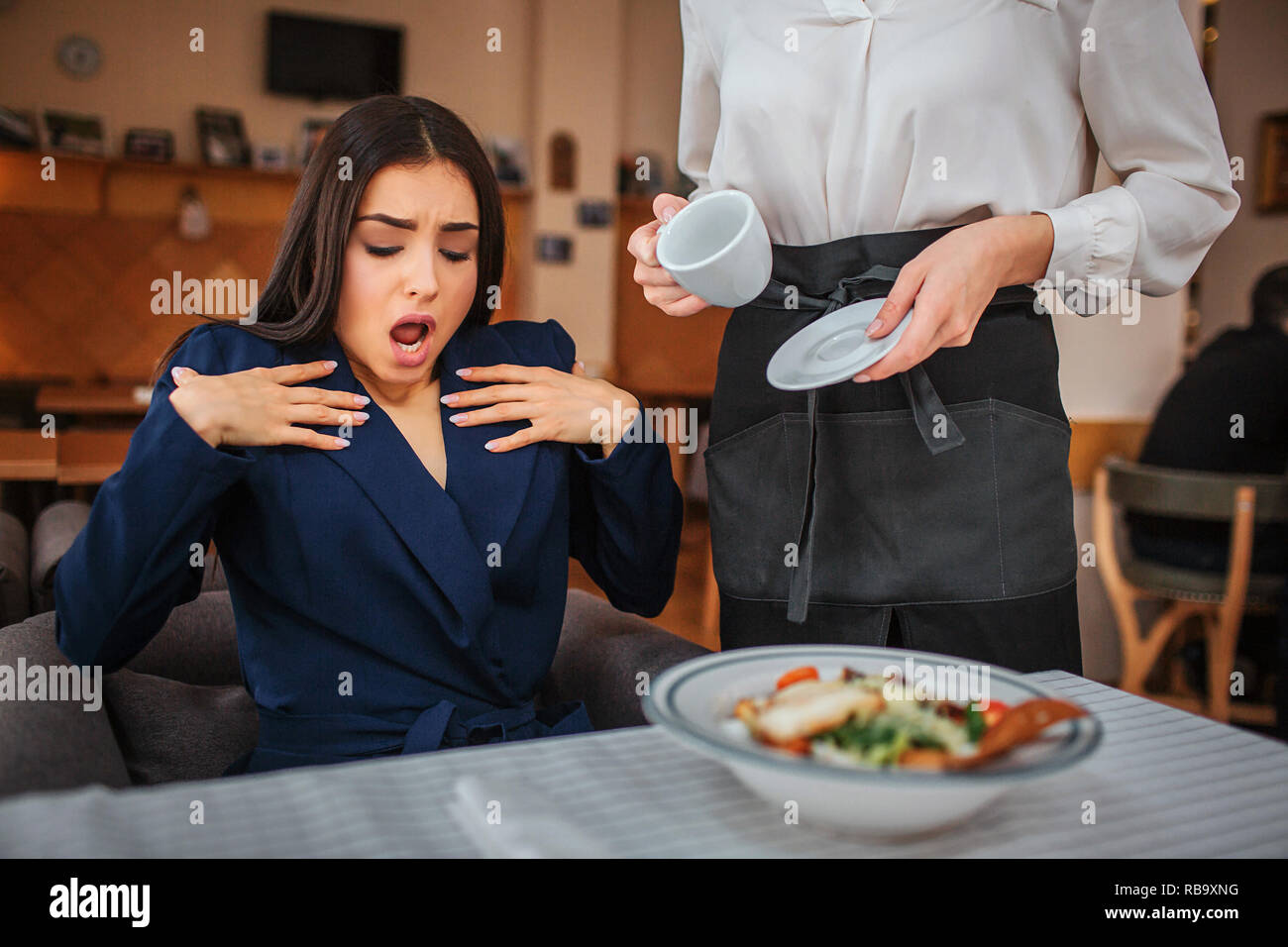 Emotional young businesswoman look down. She is amazed how waitress ...