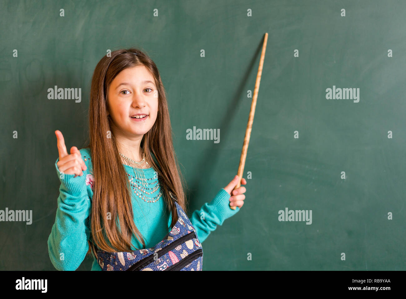 Schoolgirl stands at the blackboard with a pointer. School Child with ...