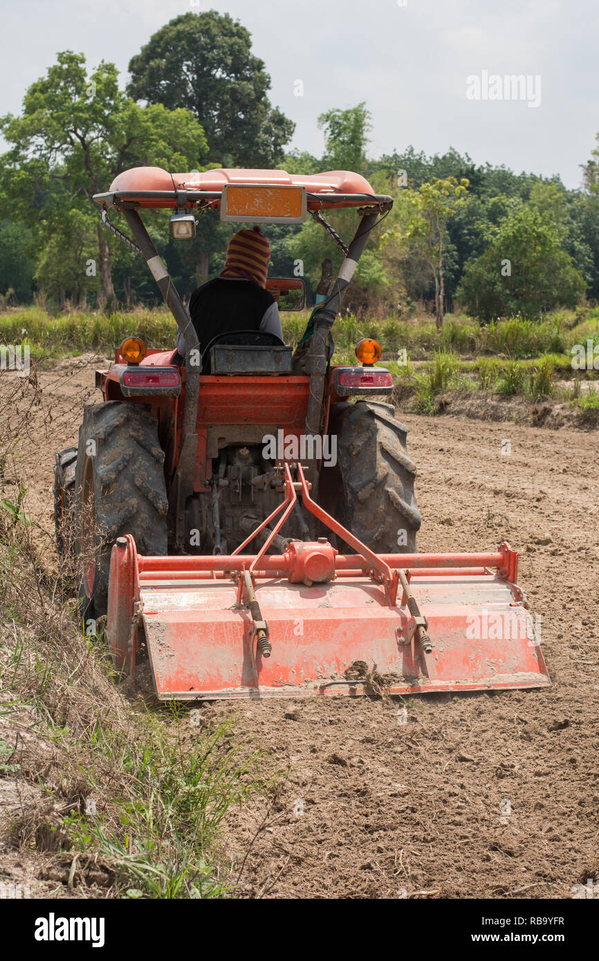 Thai farmers are using a tractor to prepare the soil for growing rice ...