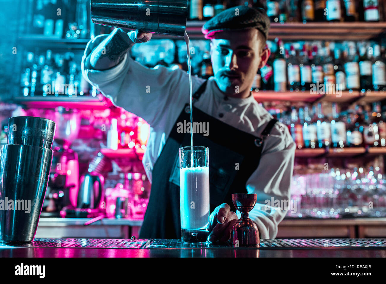 Expert barman is making cocktail at night club or bar. Glass of fiery ...