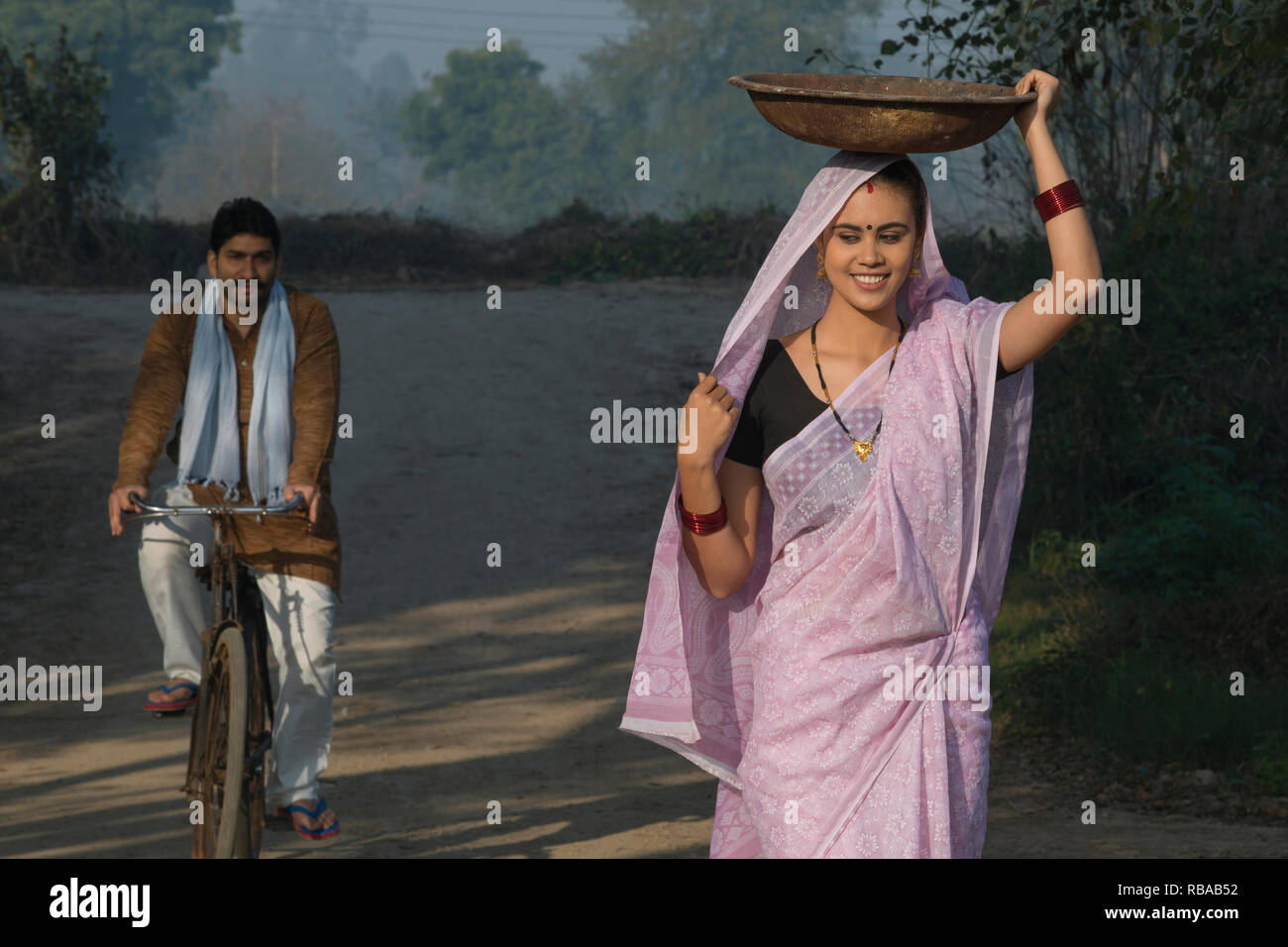 Smiling rural woman going to work carrying an iron gold pan on her head ...