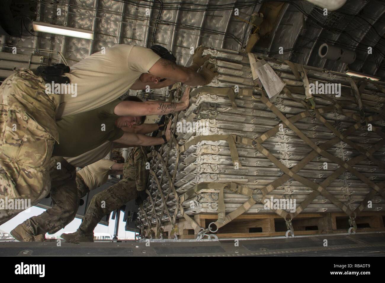 Aerial porters, a loadmaster, and a Marine all work together to push a ...