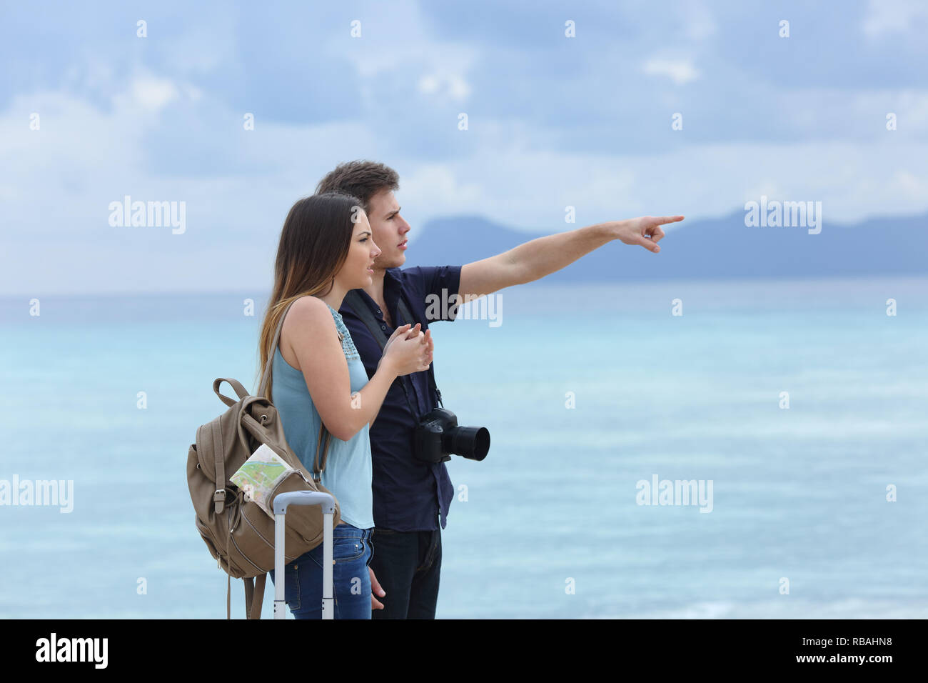 Side view portrait of two frustrated tourists pointing horizon a bad ...
