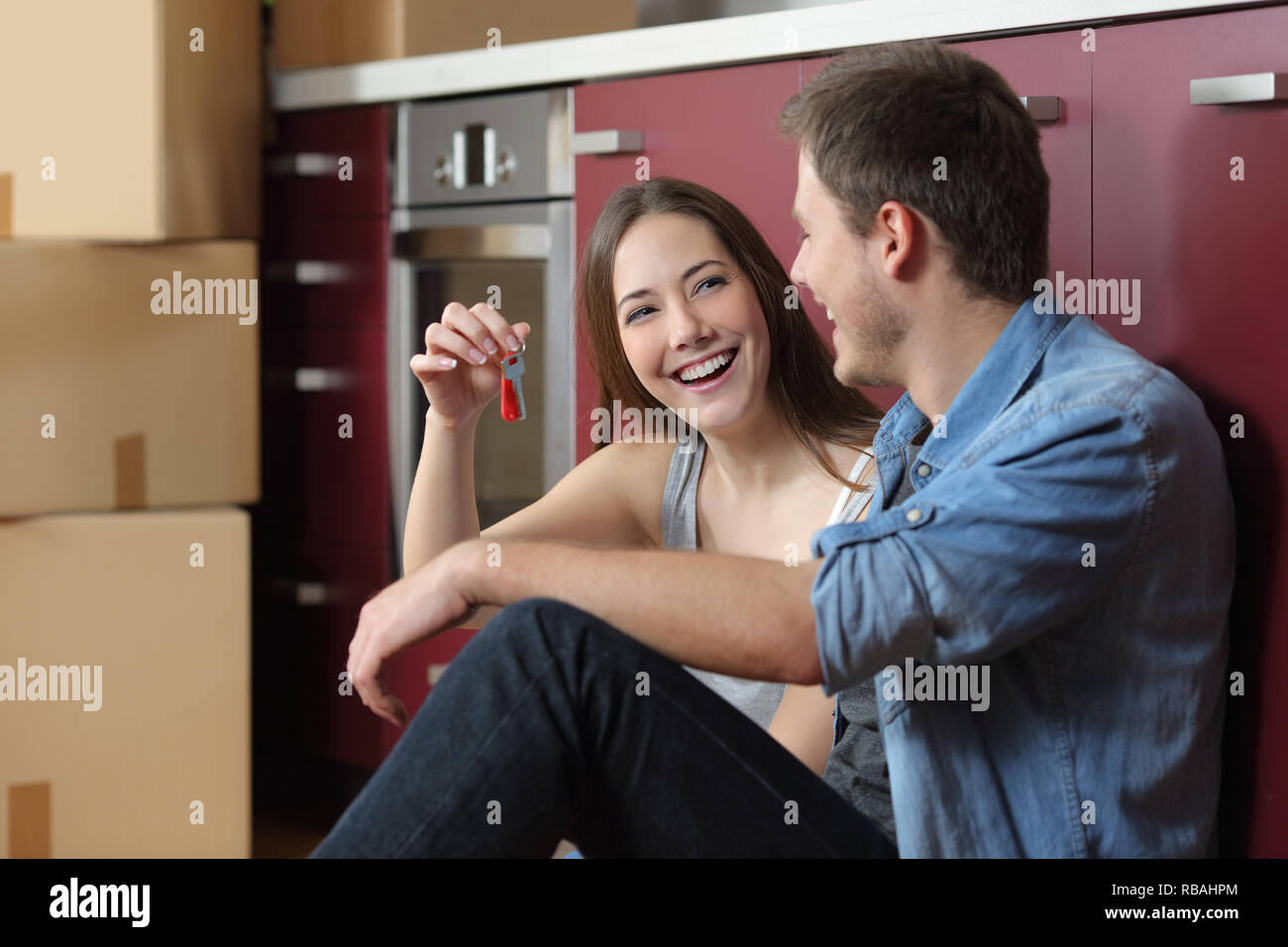Happy tenants showing new home keys sitting on the floor of the kitchen ...