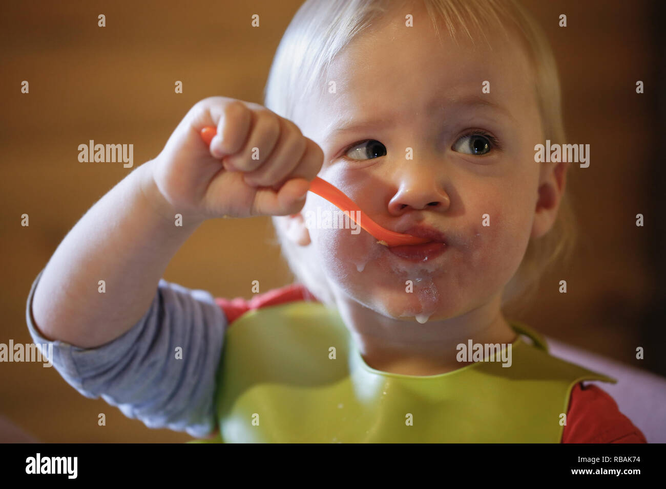 Child eating independently with a spoon, feeding himself, making a mess ...