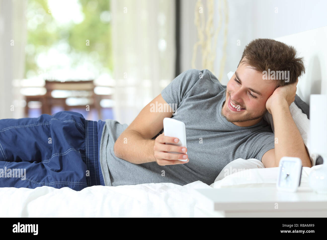 Happy man checking smart phone content lying on the bed at home Stock ...