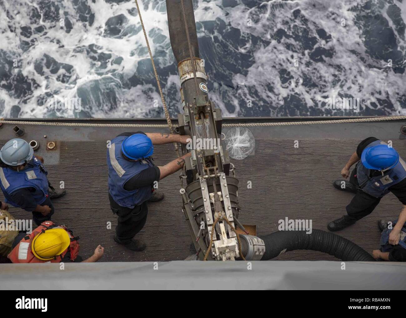 A Sailor aboard the USS Arlington (LPD 24) attaches a fuel line from ...