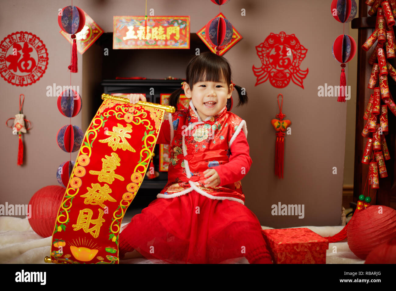 Chinese baby girl traditional dressing up with a Gong Xi Fa Cha scrolls ...