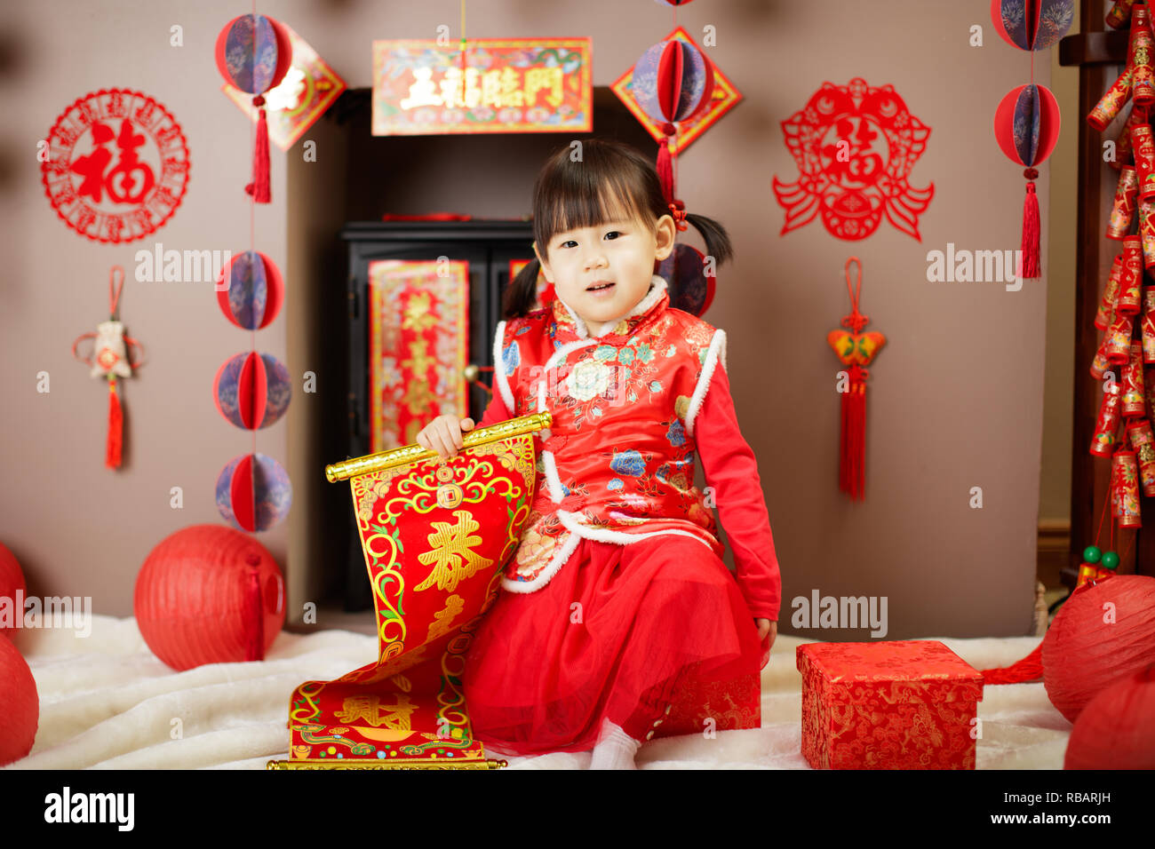 Chinese baby girl traditional dressing up with a Gong Xi Fa Cha scrolls ...