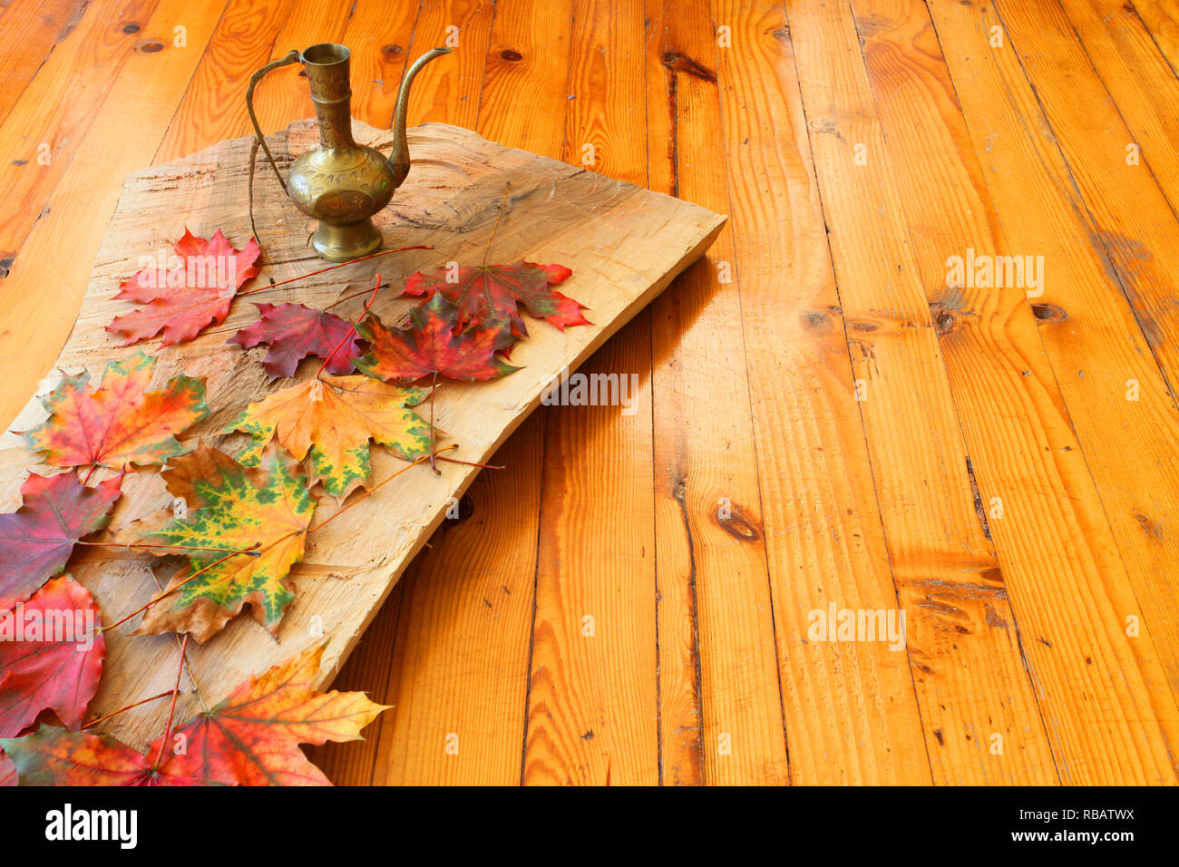 Colorful autumn leaves of Canadian oak. An old copper pot on a wooden ...