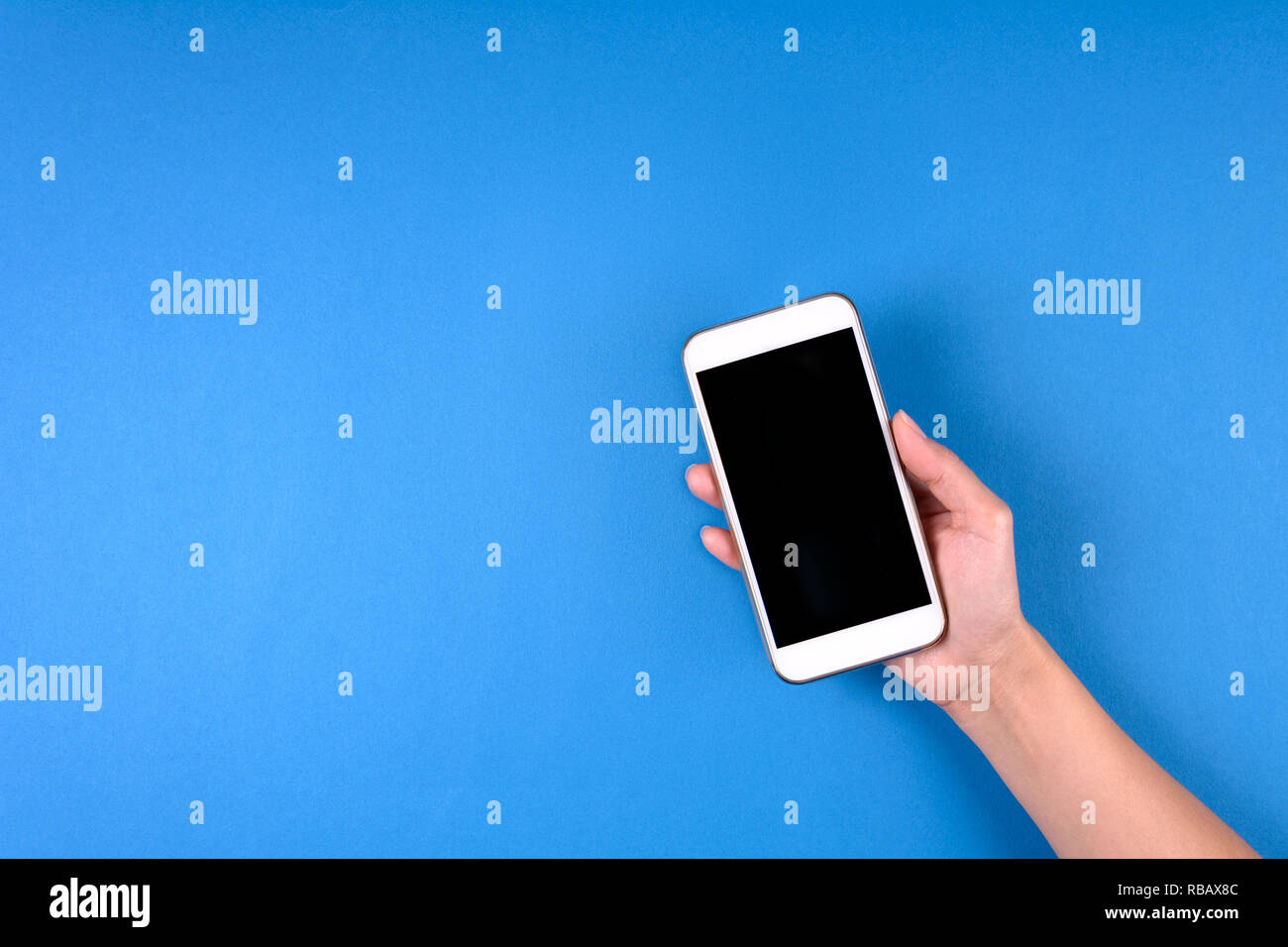 Hand touching smartphone screen on blue background. Mock-up. Top view ...