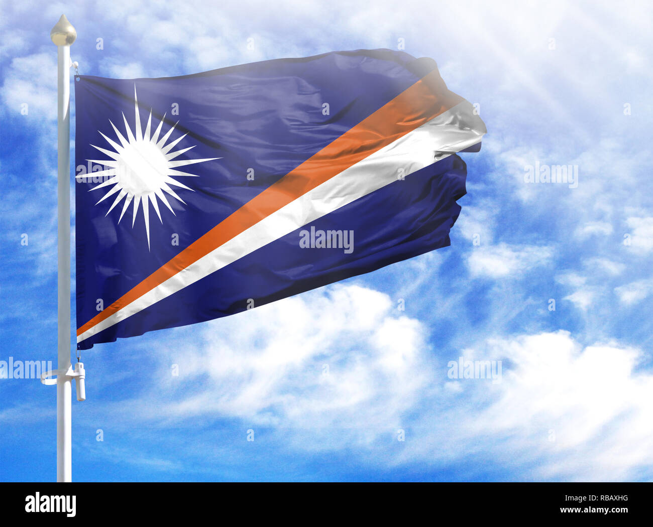 National flag of Marshall Islands on a flagpole in front of blue sky ...