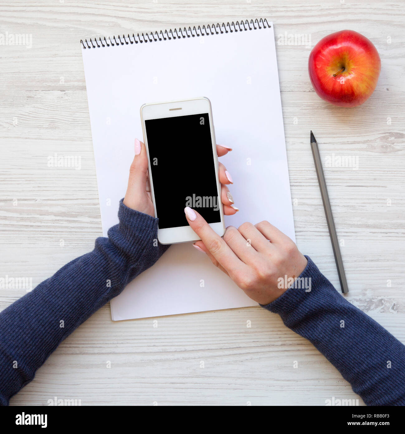 Feminine workspace with smartphone, notepad and apple. Overhead, top ...