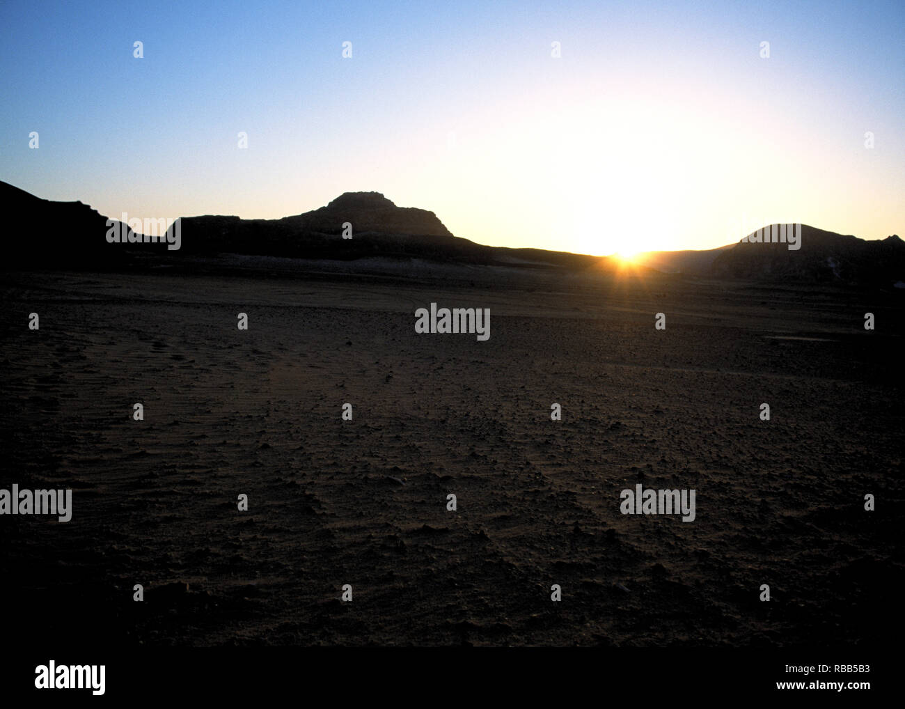 Sun setting behind desert rock formations Stock Photo - Alamy