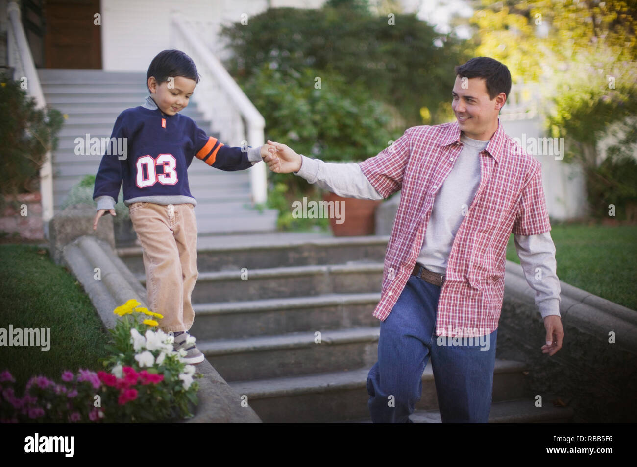 father helps son walk along ledge Stock Photo - Alamy