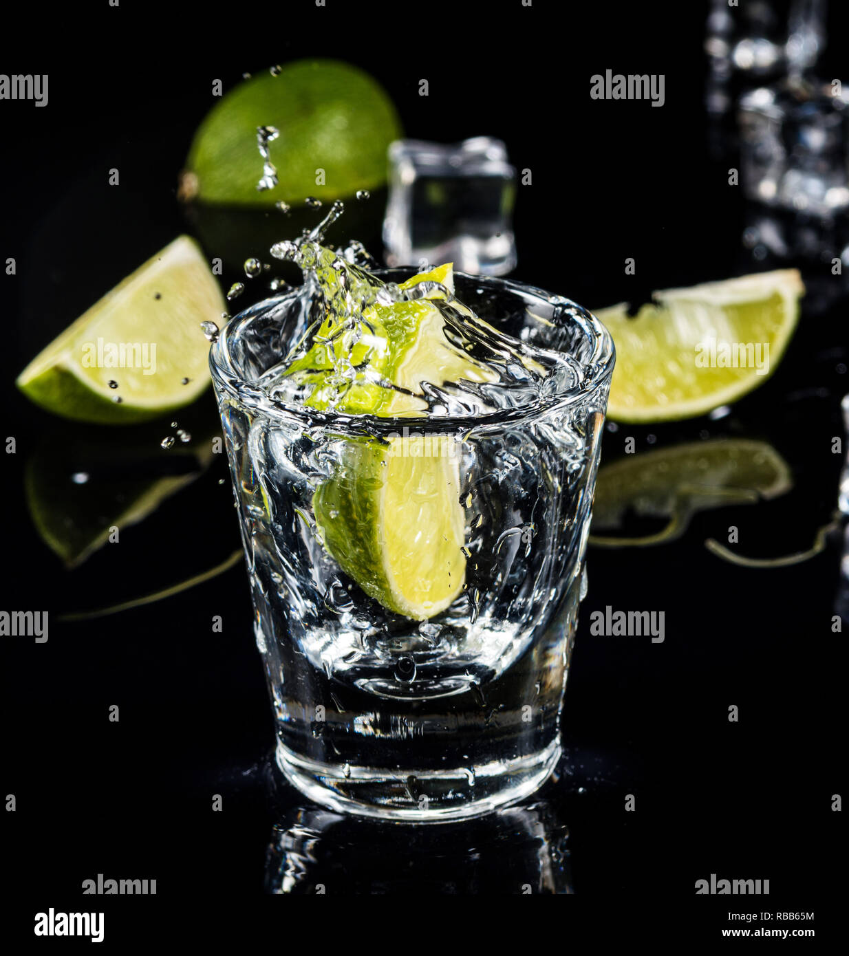 Mexican traditional Tequila splash lime on black background with ice ...