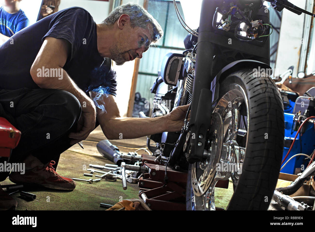 Side view portrait of man working in garage repairing motorcycle Stock ...