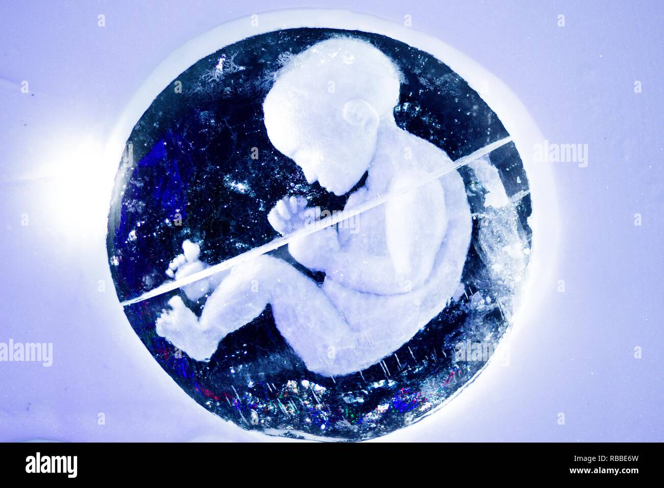 Snow figure of a small child under a layer of cold ice. The figure is ...