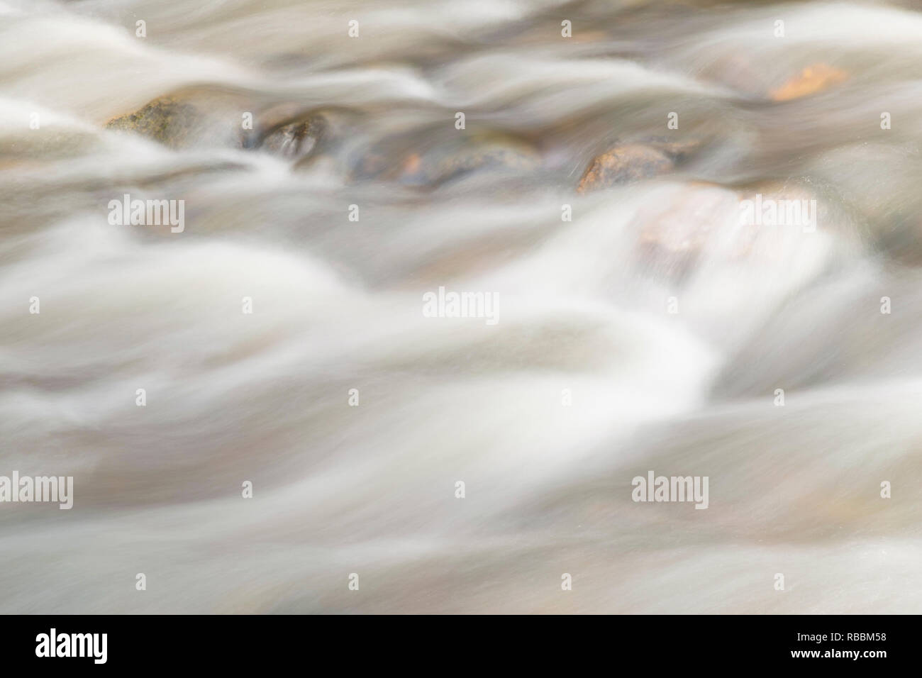 close up of fast flowig river showing rocks with slow shutter showing ...