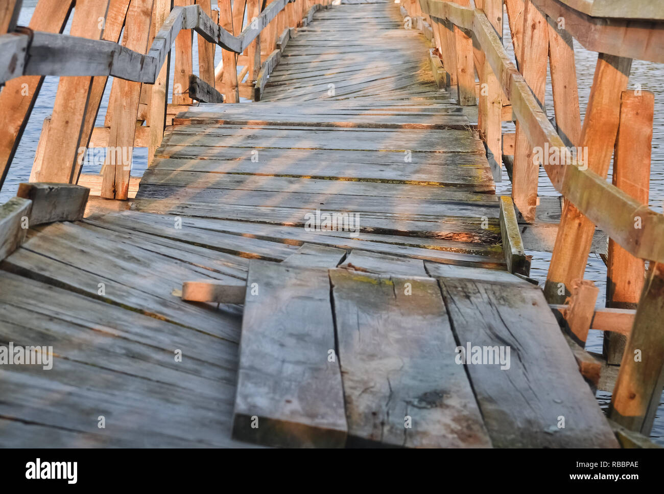 Detail of a deformed wooden bridge over a small river Stock Photo - Alamy