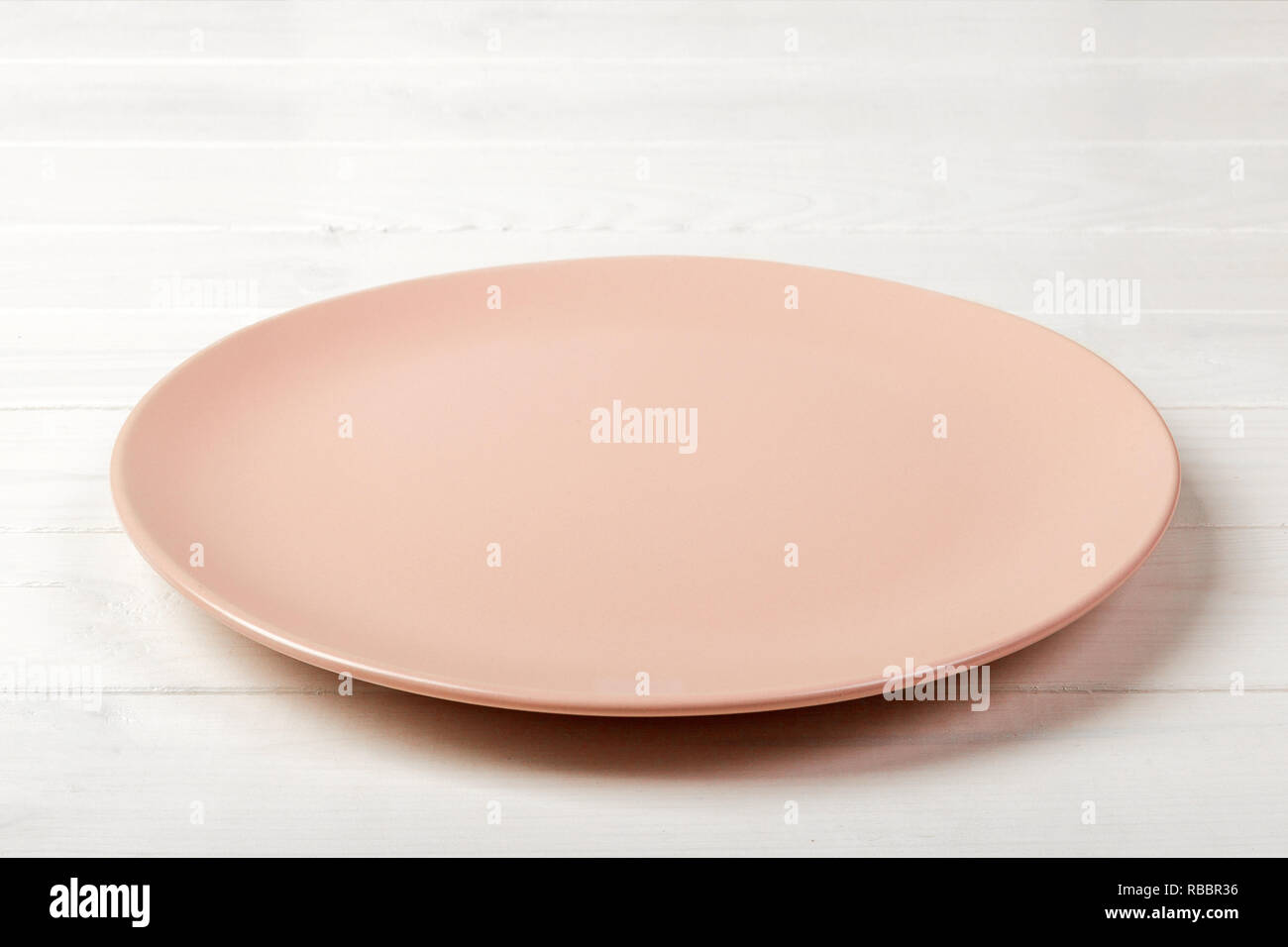Perspective view. Empty pink matte plate on white wooden background ...