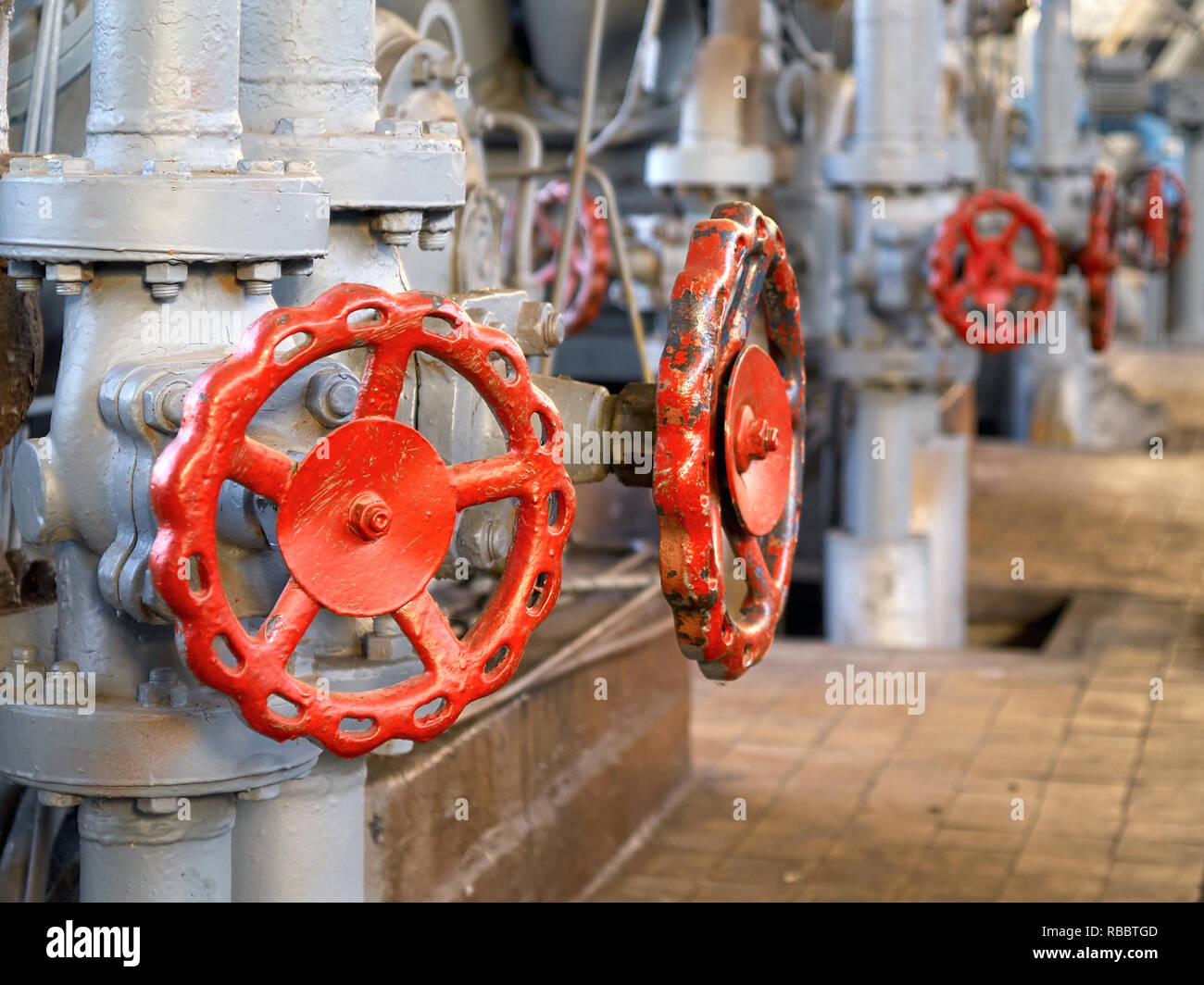 Red valves and latches on background of gray pipelines and compressors ...