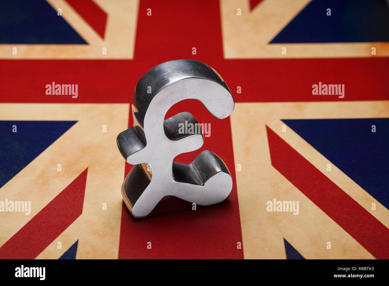 A silver pound symbol sitting on a Union Jack flag Stock Photo - Alamy