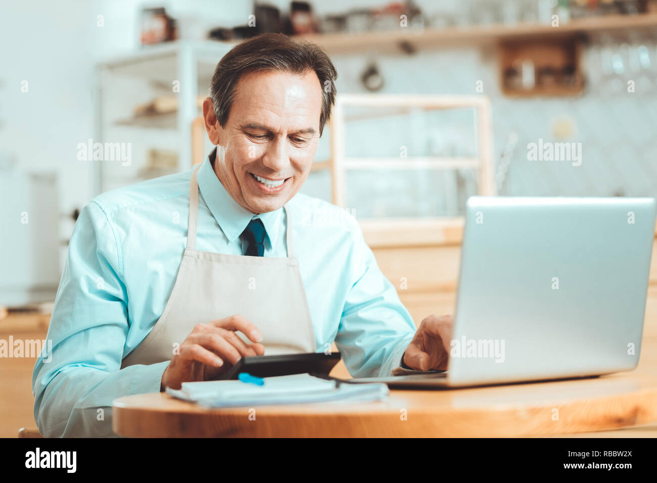 Satisfying results. Cheerful nice owner making calculations analyzing ...