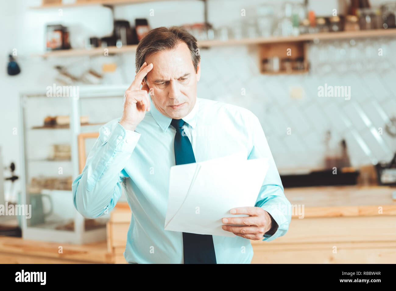 Feeling upset. Smart concentrated man reading a letter from business ...