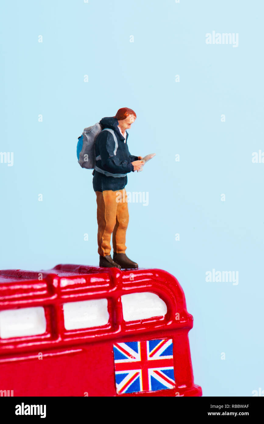 miniature backpacker man on the top of a red double-decker bus, typical ...