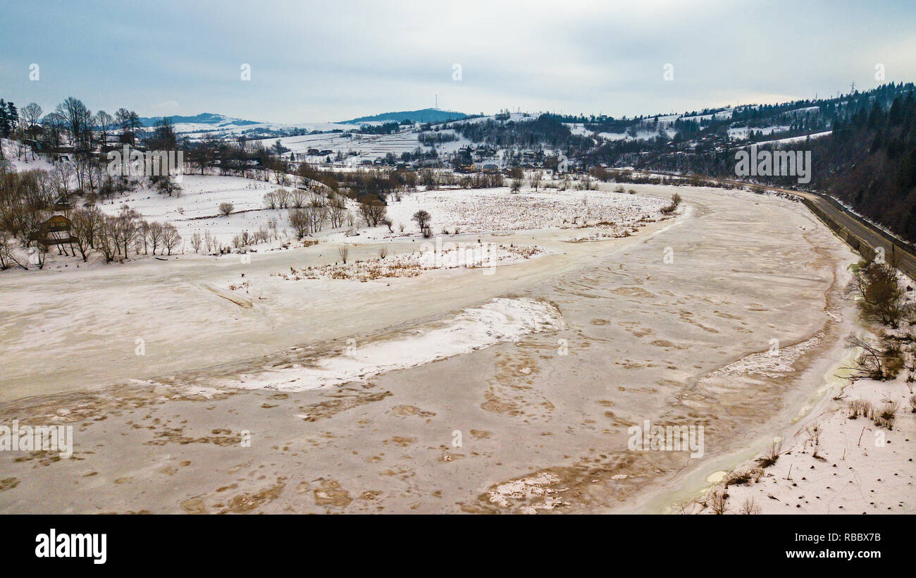 Frozen winter river. Aerial rural view of snowy village and road ...