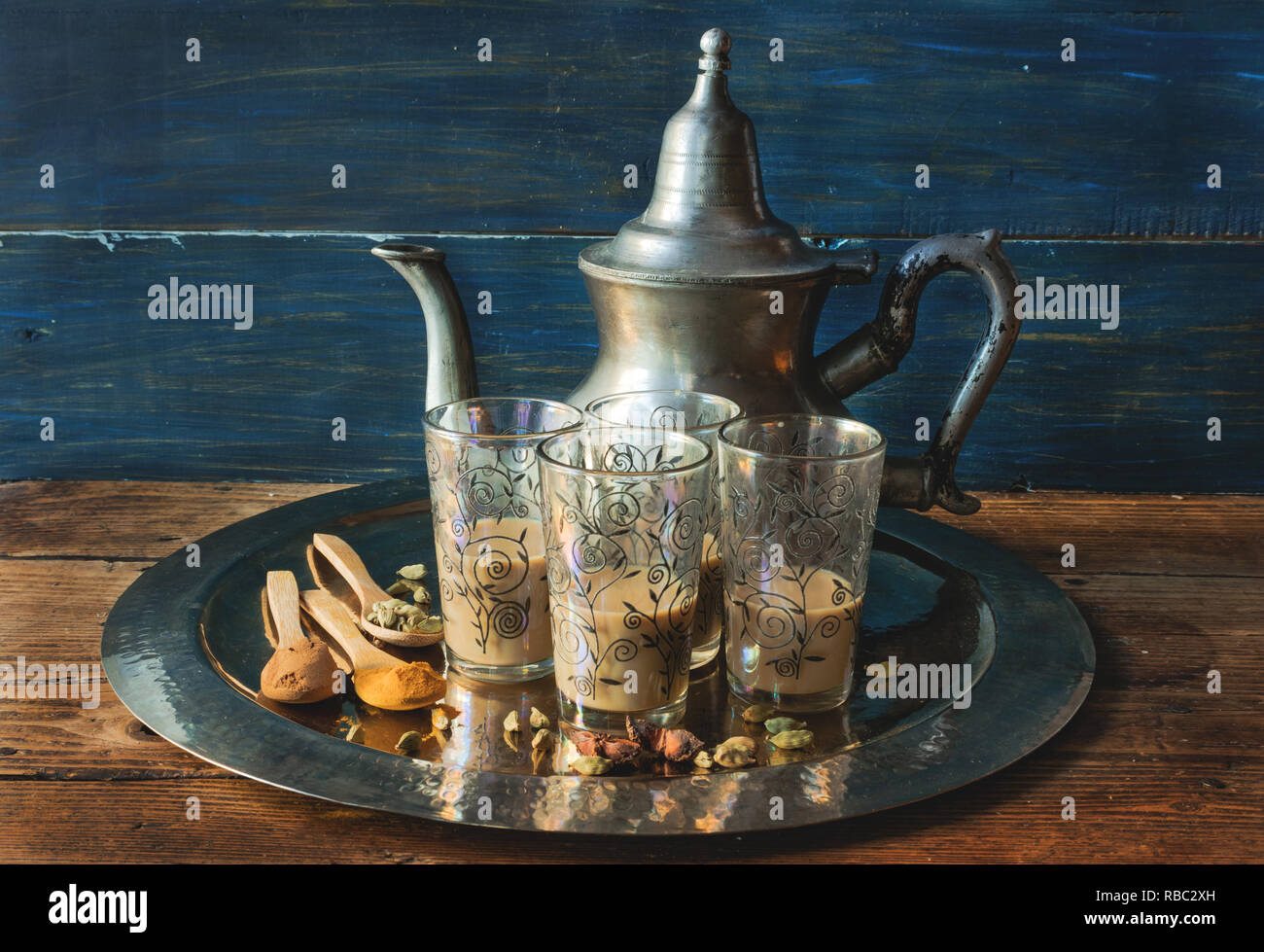 glass cups of Pakistani tea with spices in a tray and teapot, seen from ...