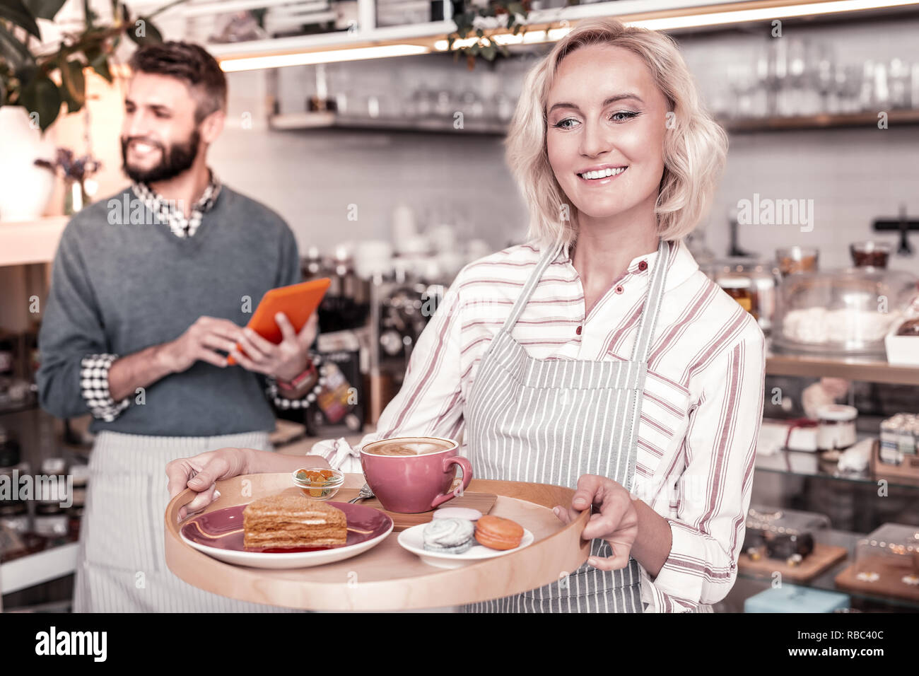 Positive friendly woman serving the order to customers Stock Photo - Alamy