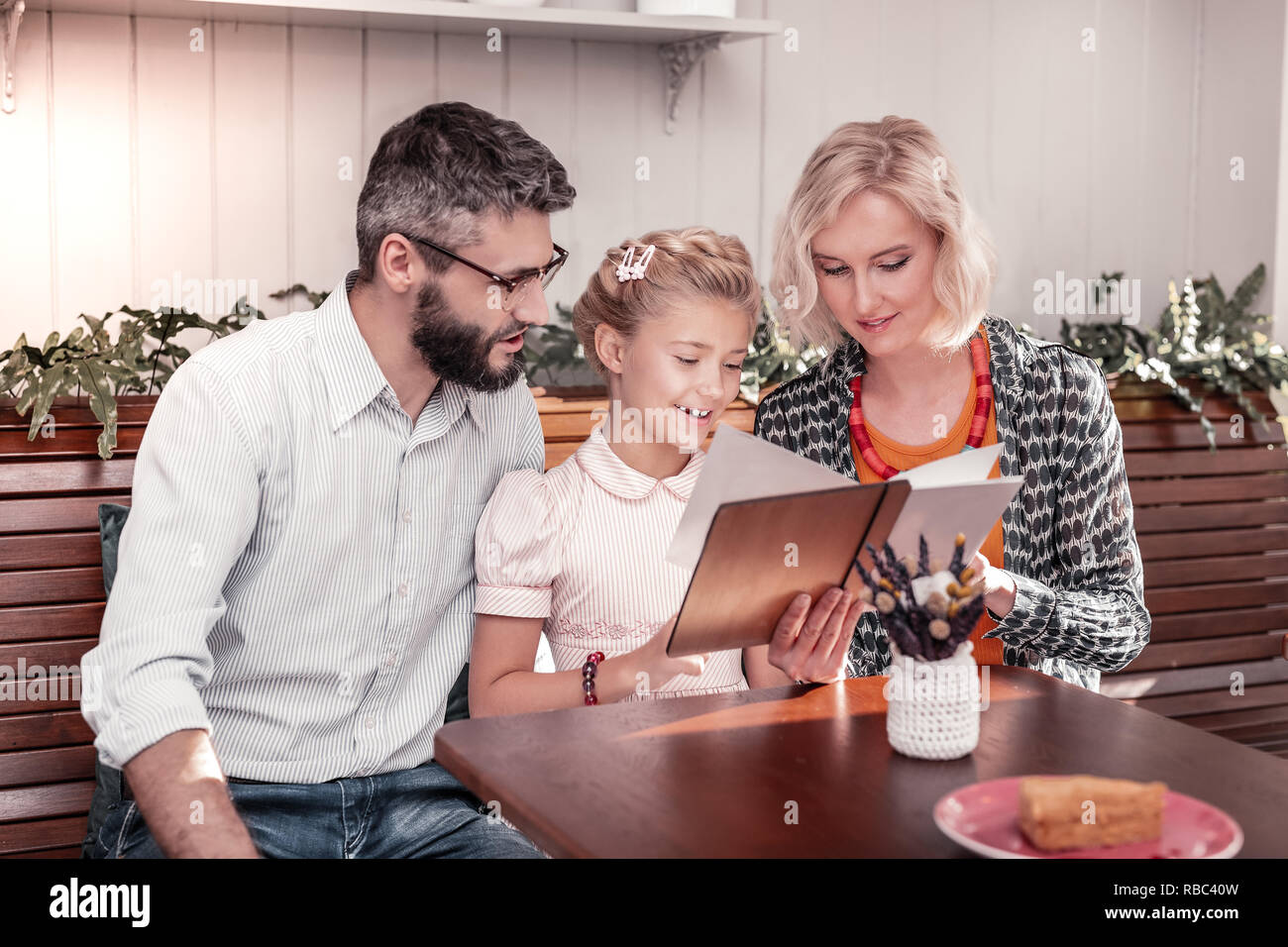 Joyful positive cute girl reading the menu Stock Photo - Alamy