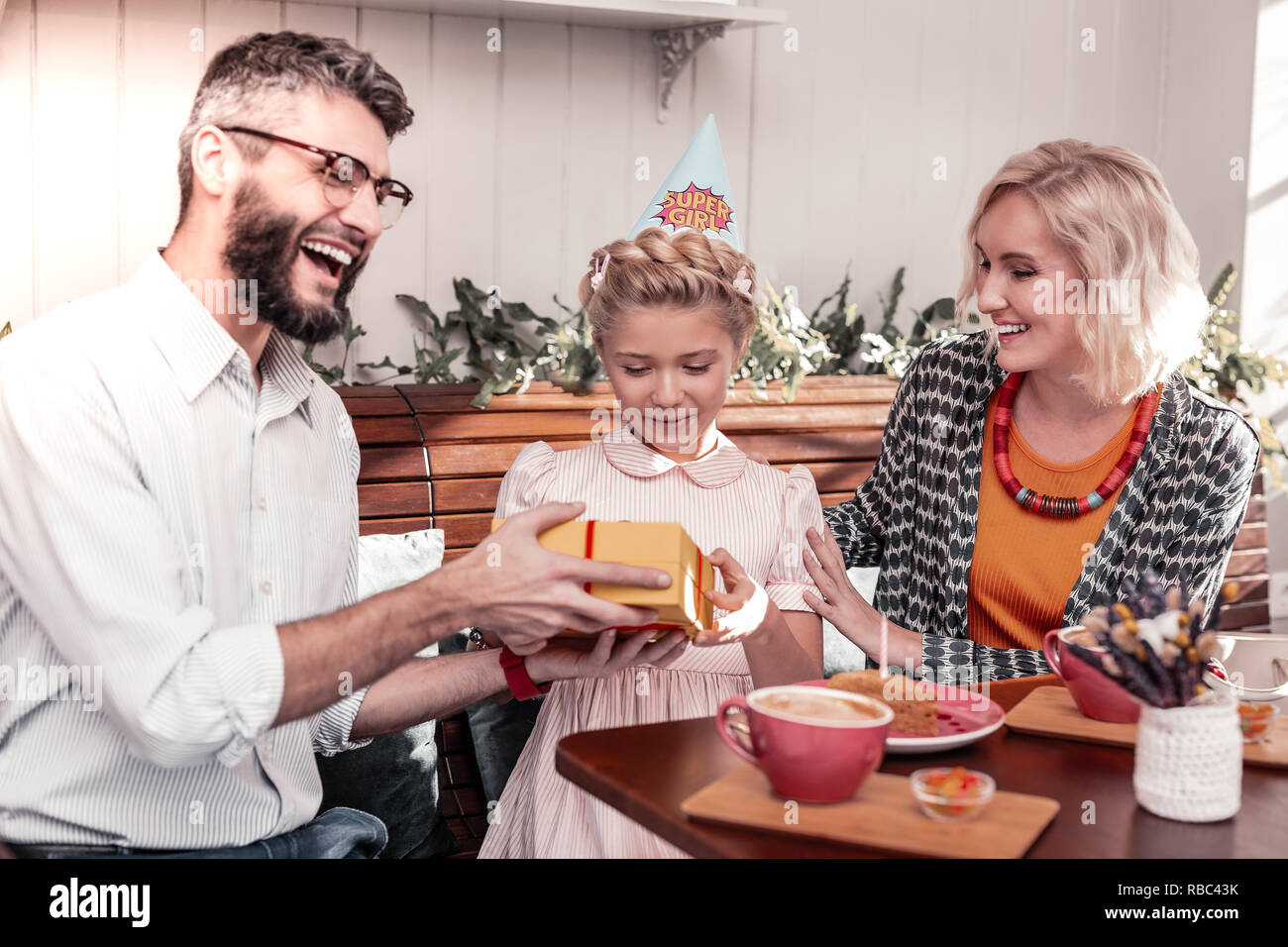 Nice delighted girl taking her birthday present Stock Photo - Alamy