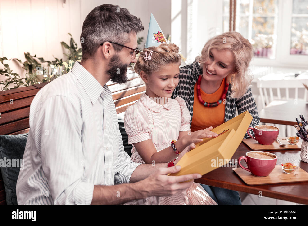 Nice positive cute girl opening her present Stock Photo - Alamy