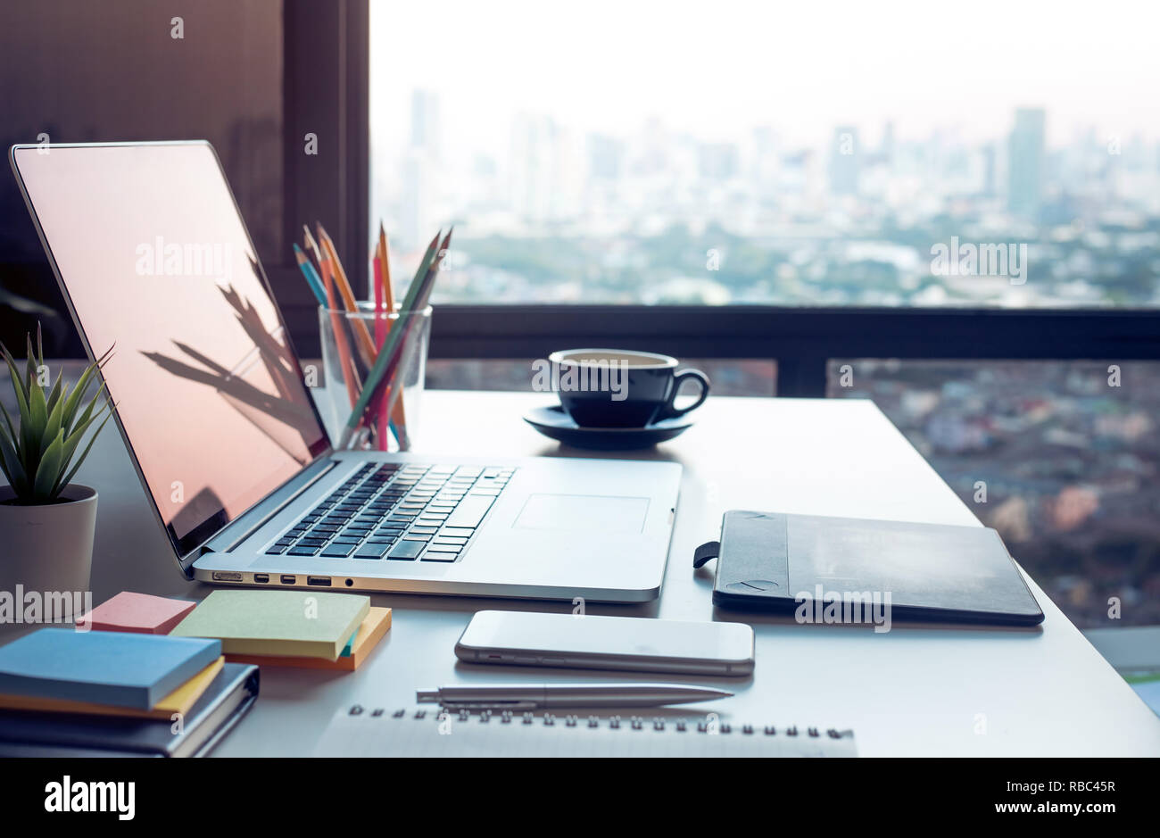 Modern work table with computer laptop and cityscapes view from window ...