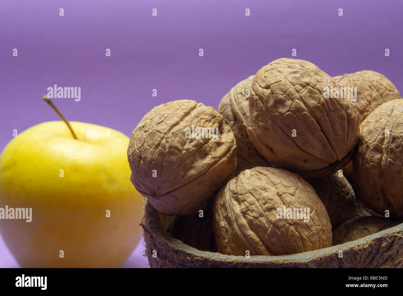 Pile of whole common walnuts with shells in natural coconut shell cup ...