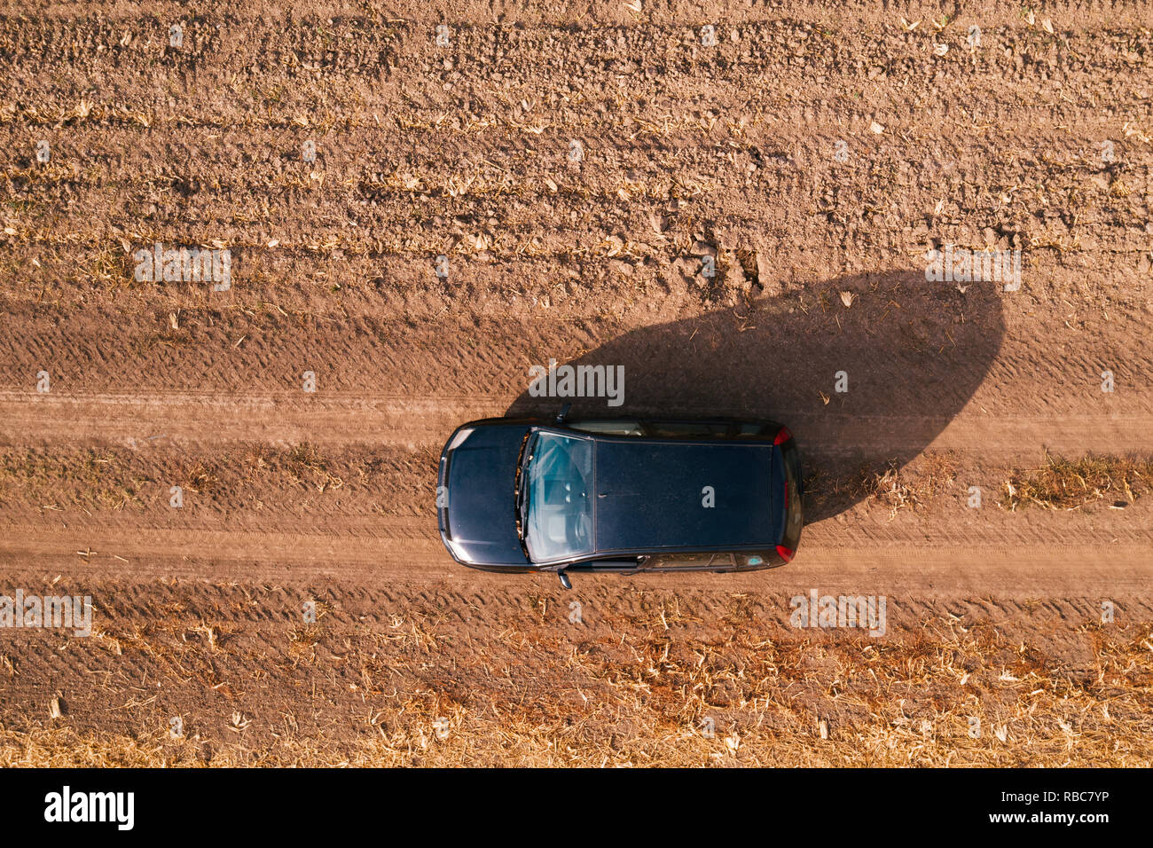 Aerial view of black car on dirt road through countryside, top view ...
