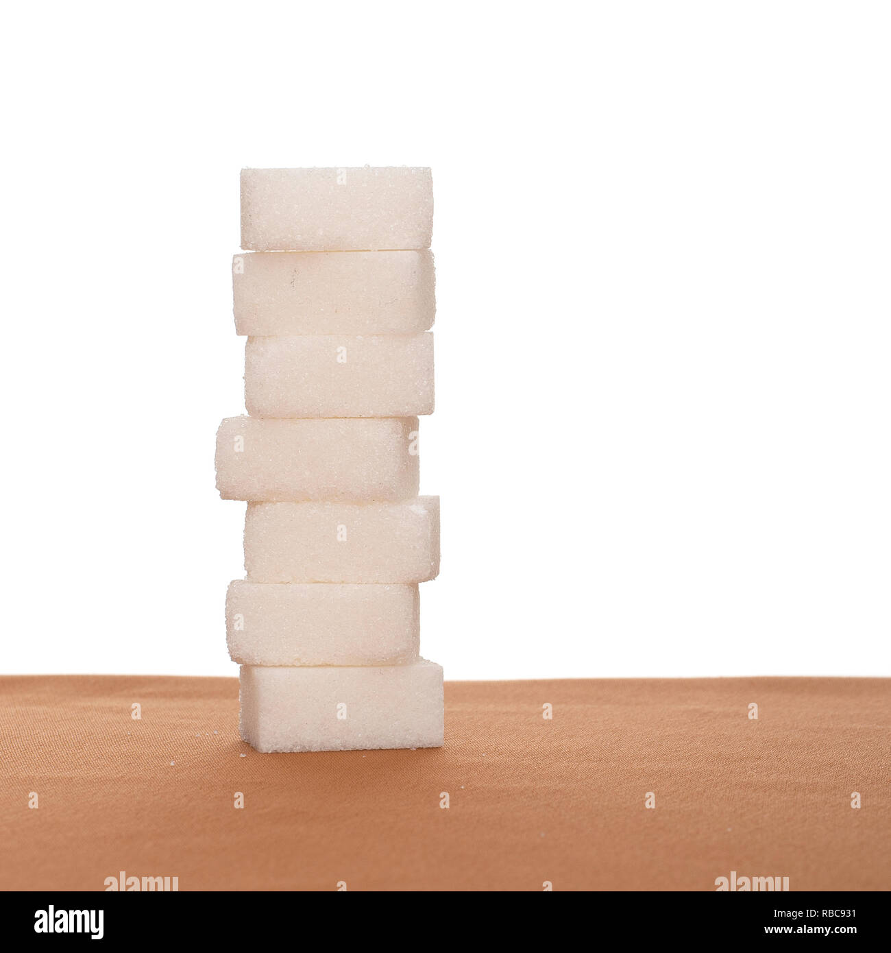Stack of seven sugar cubes on fabric, white background. Healthy eating ...