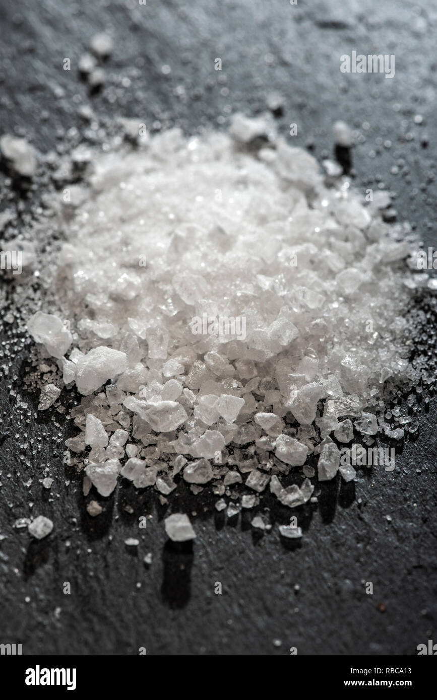 White salt crushed on dark stone background. Close-up Big pieces of ...