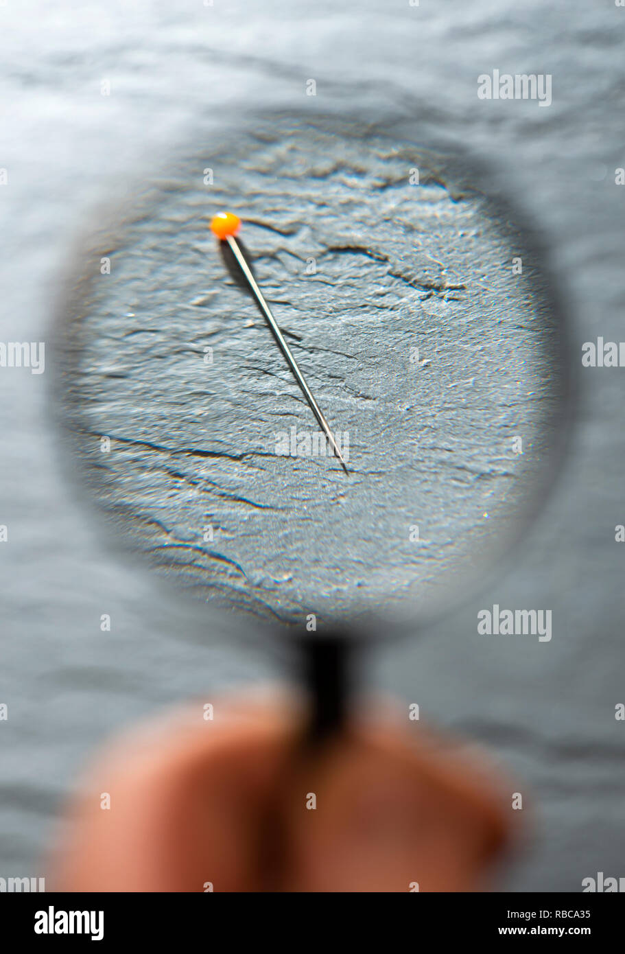 View small Needle through magnifying glass on a dark background ...